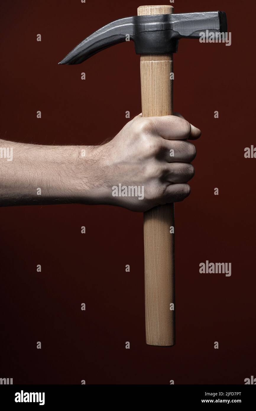 Man's hand holding hammer on red background Stock Photo - Alamy