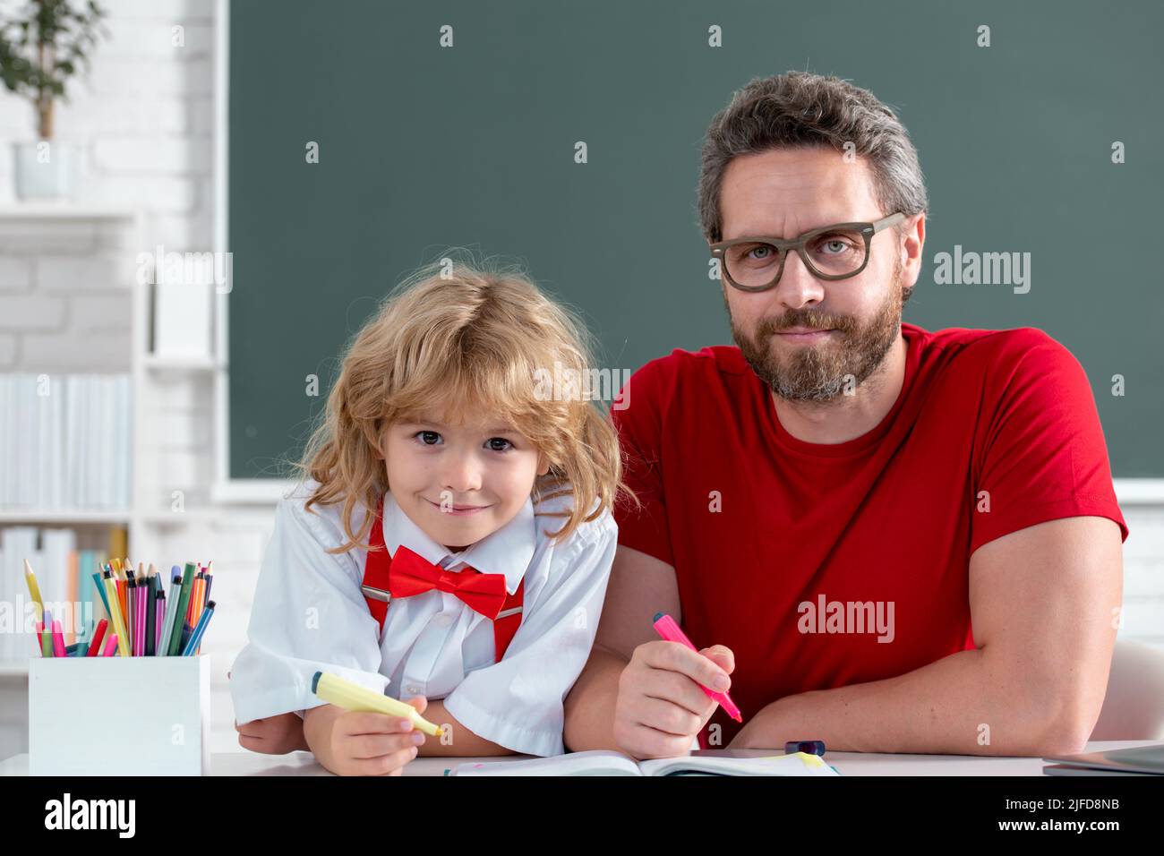 Tutor and child learning at school classroom. Teacher and little ...