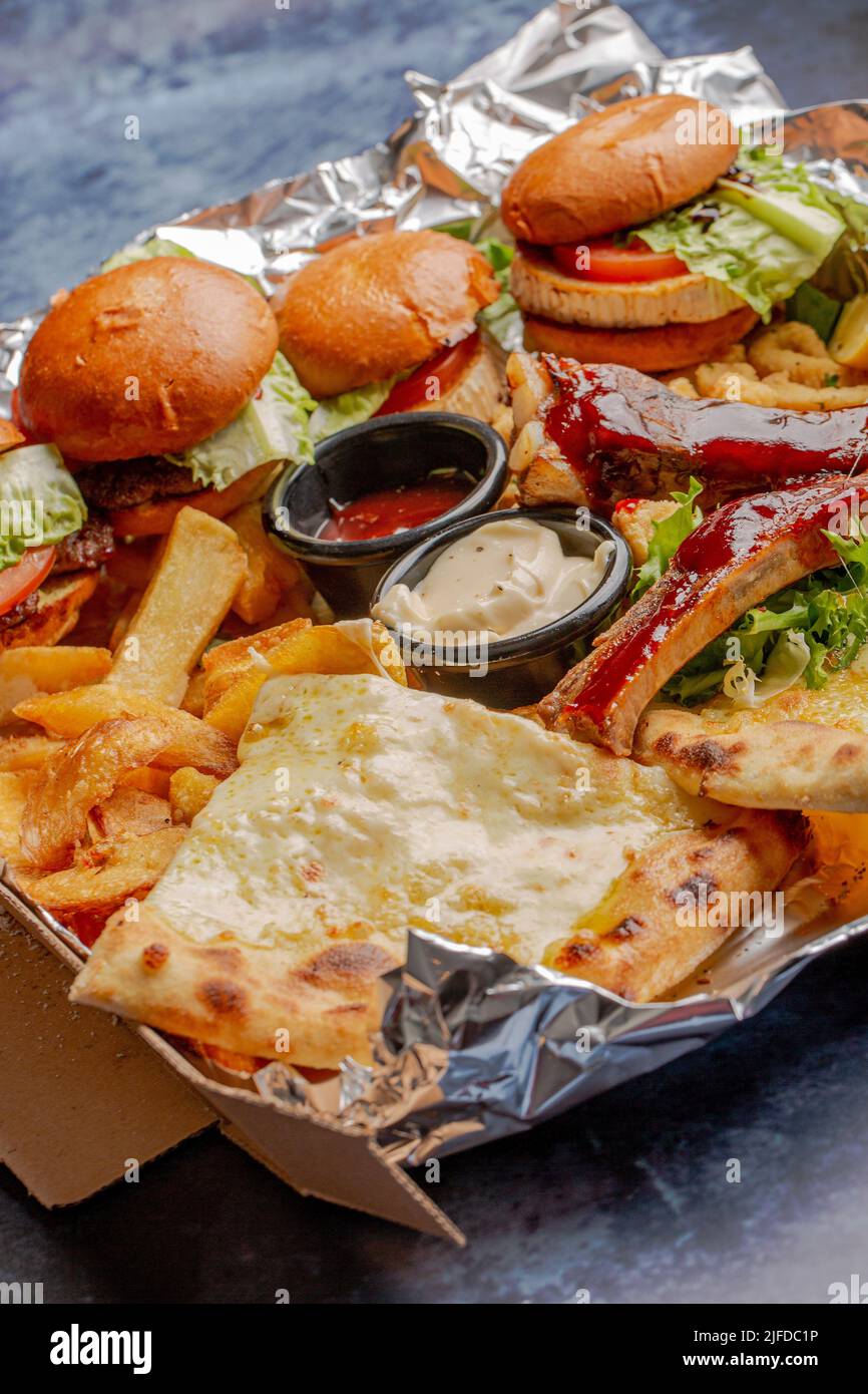 A closeup of variety of fast food including burgers, pizza, fries on ...