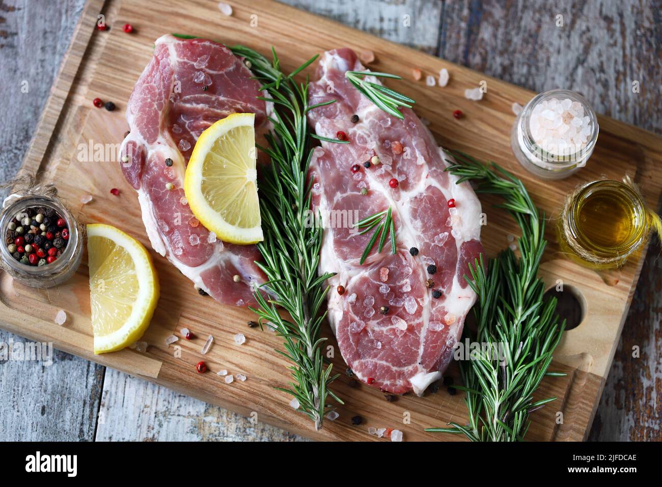 Raw pork steaks with rosemary, coarse salt and lemon. Fresh pork. Neck ...