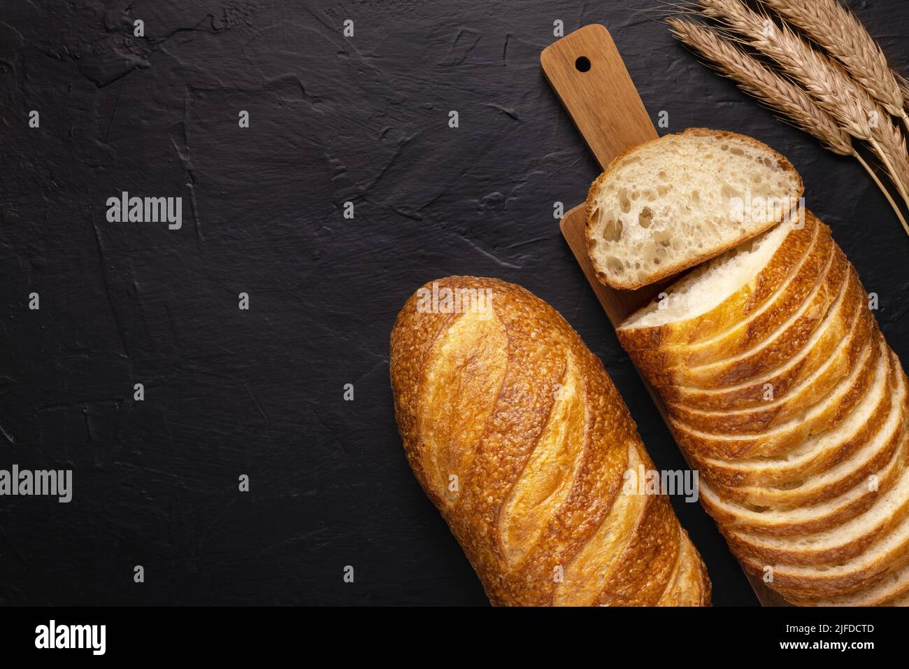Fresh wheaten baton bread on dark background. Top view. Copy space ...