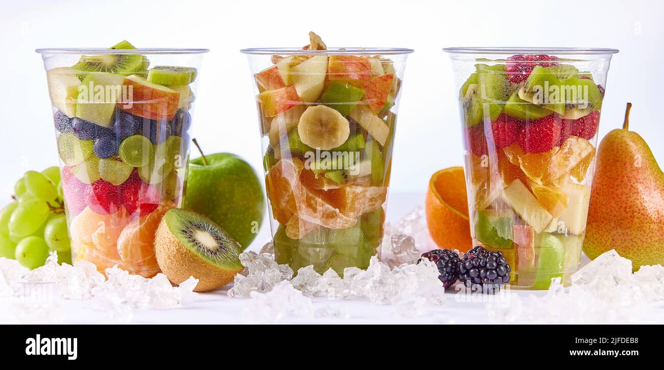 Assorted ripe chopped fruits and berries in takeaway cups placed on ...