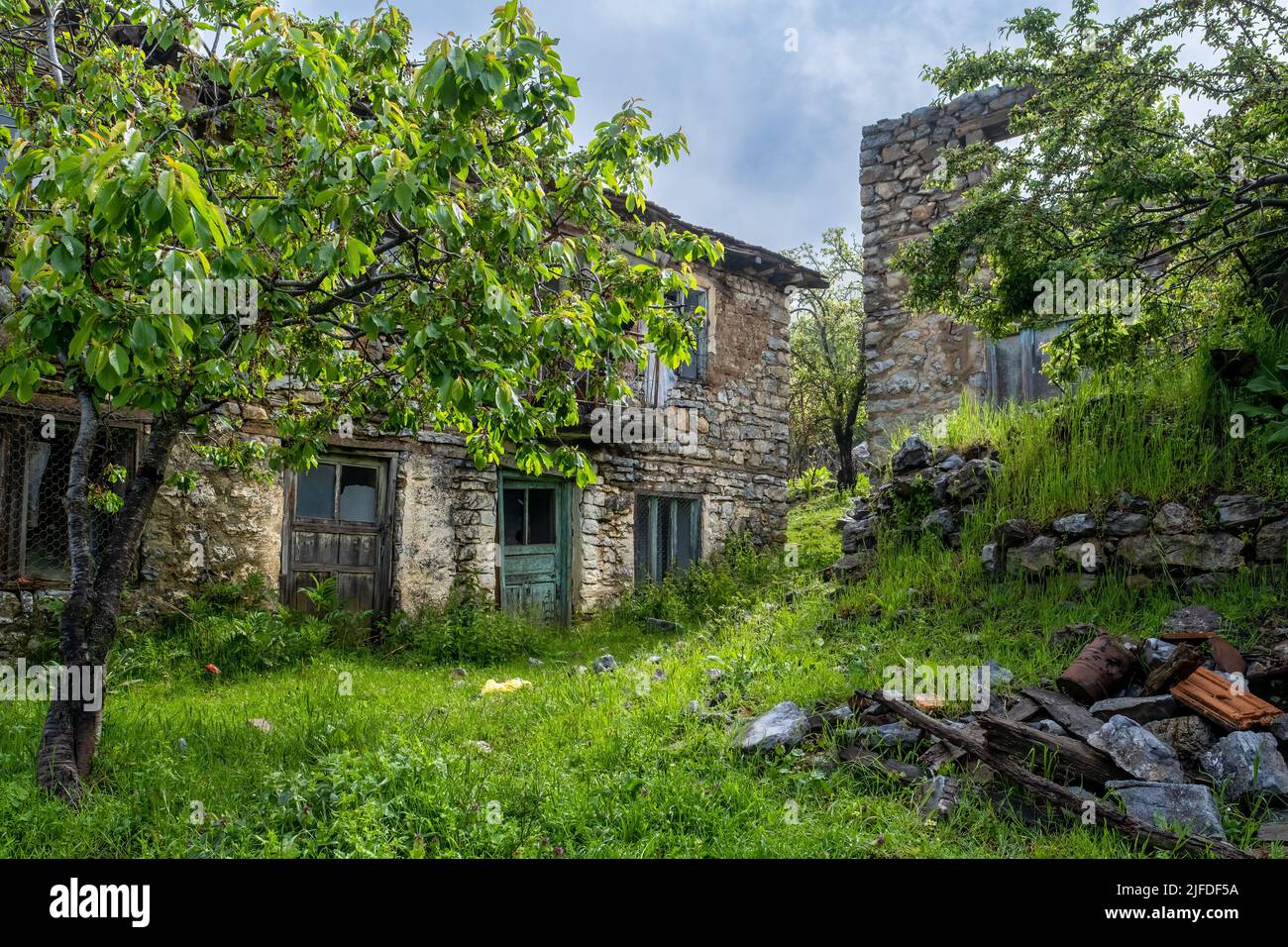 rough destroyed stone buildings in green garden in abandoned village in ...
