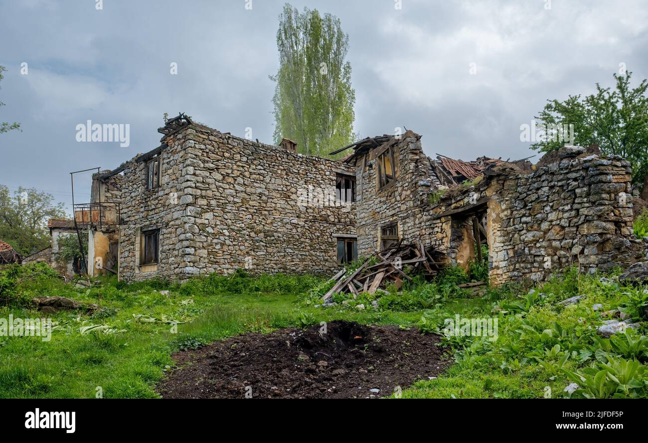old destroyed stone buildings in grass garden in abandoned village in ...