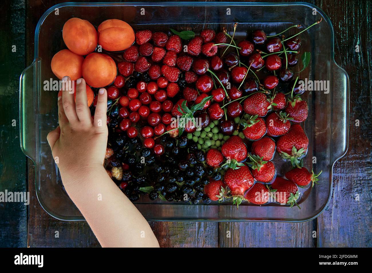 Baby washes fresh seasonal fruits and berries: strawberries, apricots ...