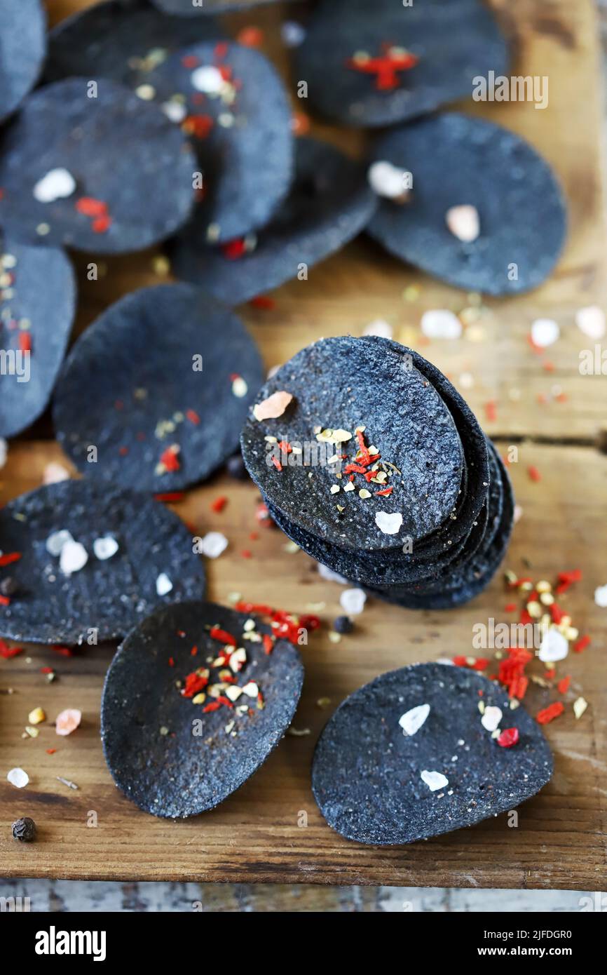 Black food. Black chips with spices on a plate. Black food trend ...