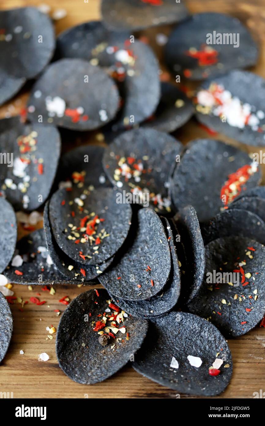 Black food. Black chips with spices on a plate. Black food trend ...