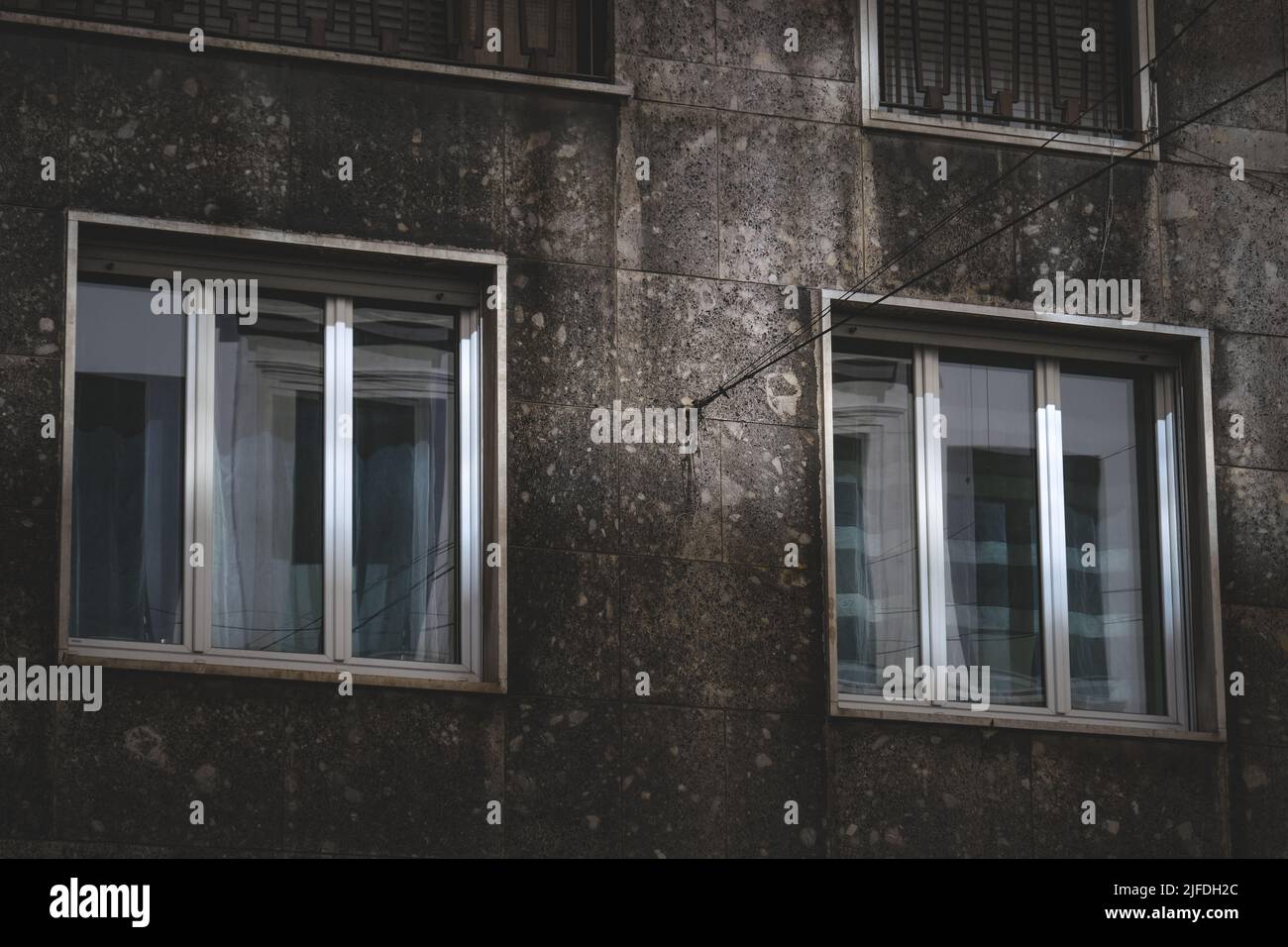 A gray apartment building with white windows Stock Photo - Alamy