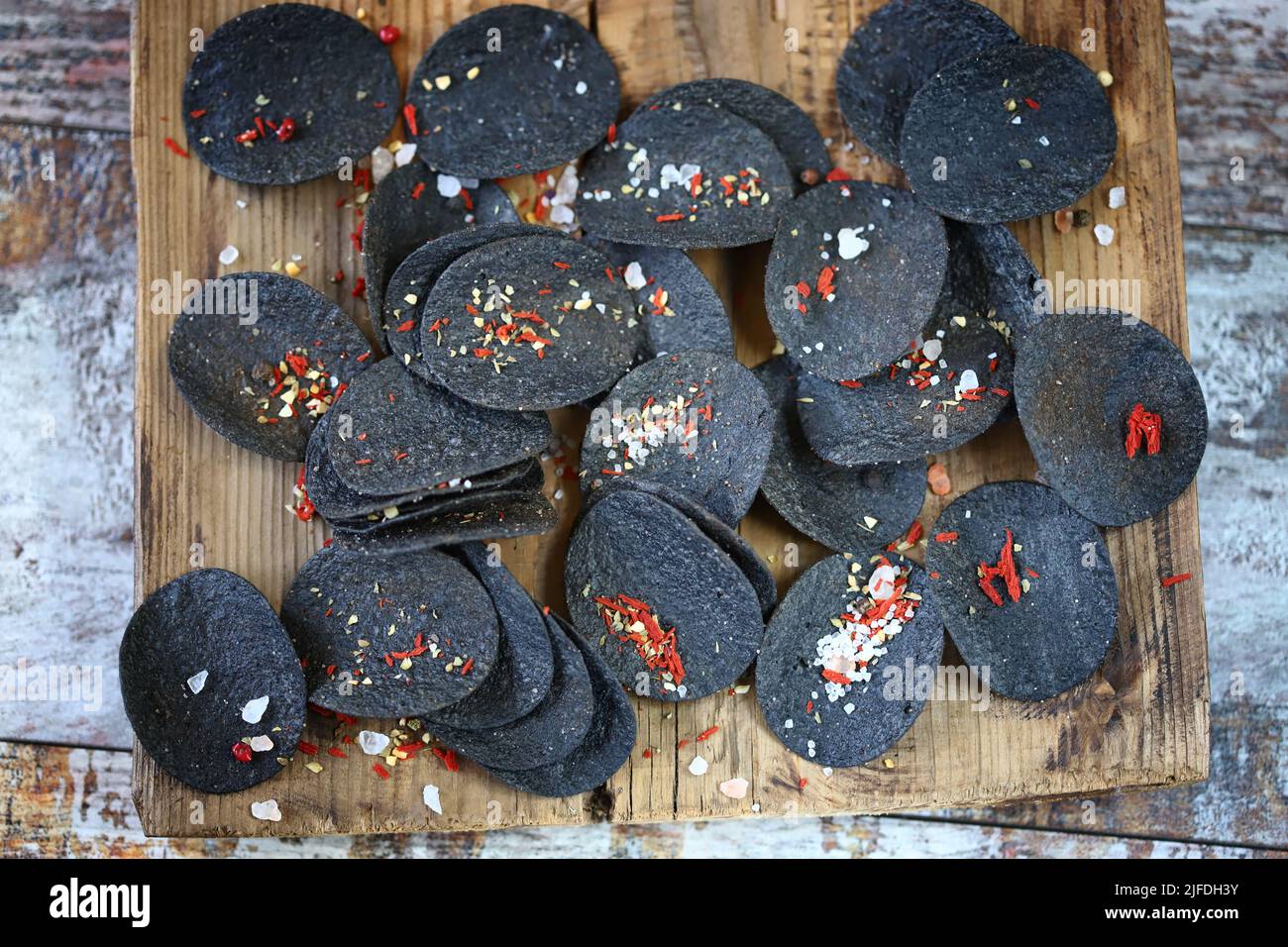 Black food. Black chips with spices on a plate. Black food trend ...