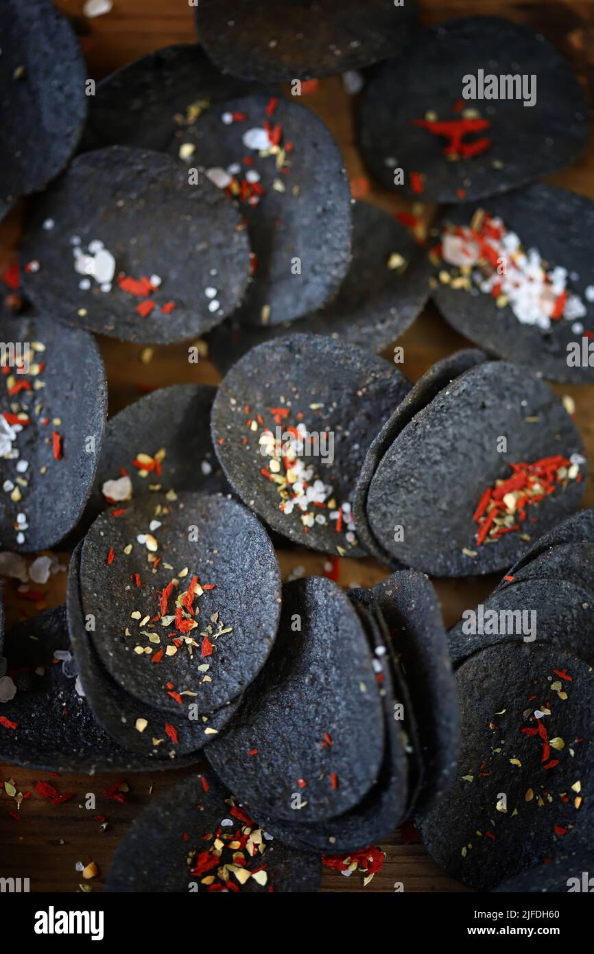 Black food. Black chips with spices on a plate. Black food trend ...