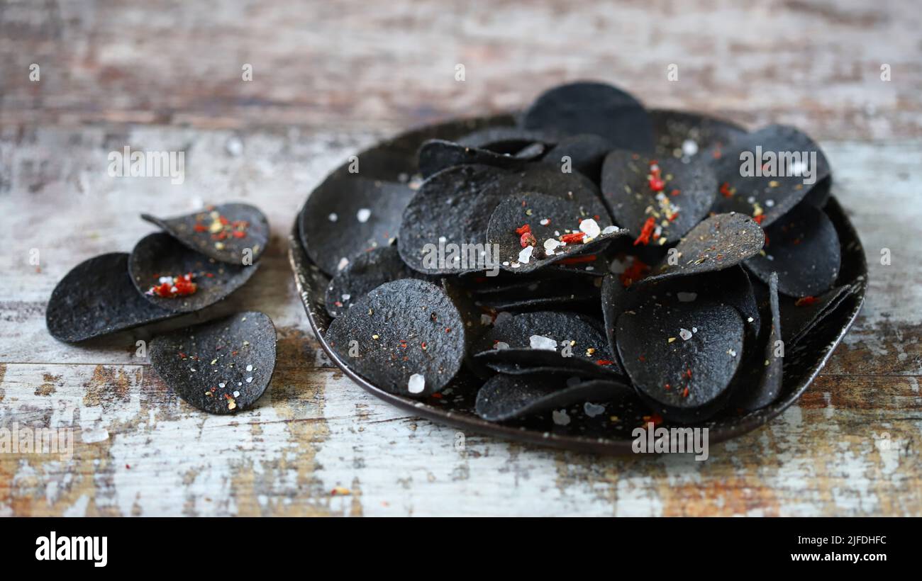 Black food. Black chips with spices on a plate. Black food trend ...