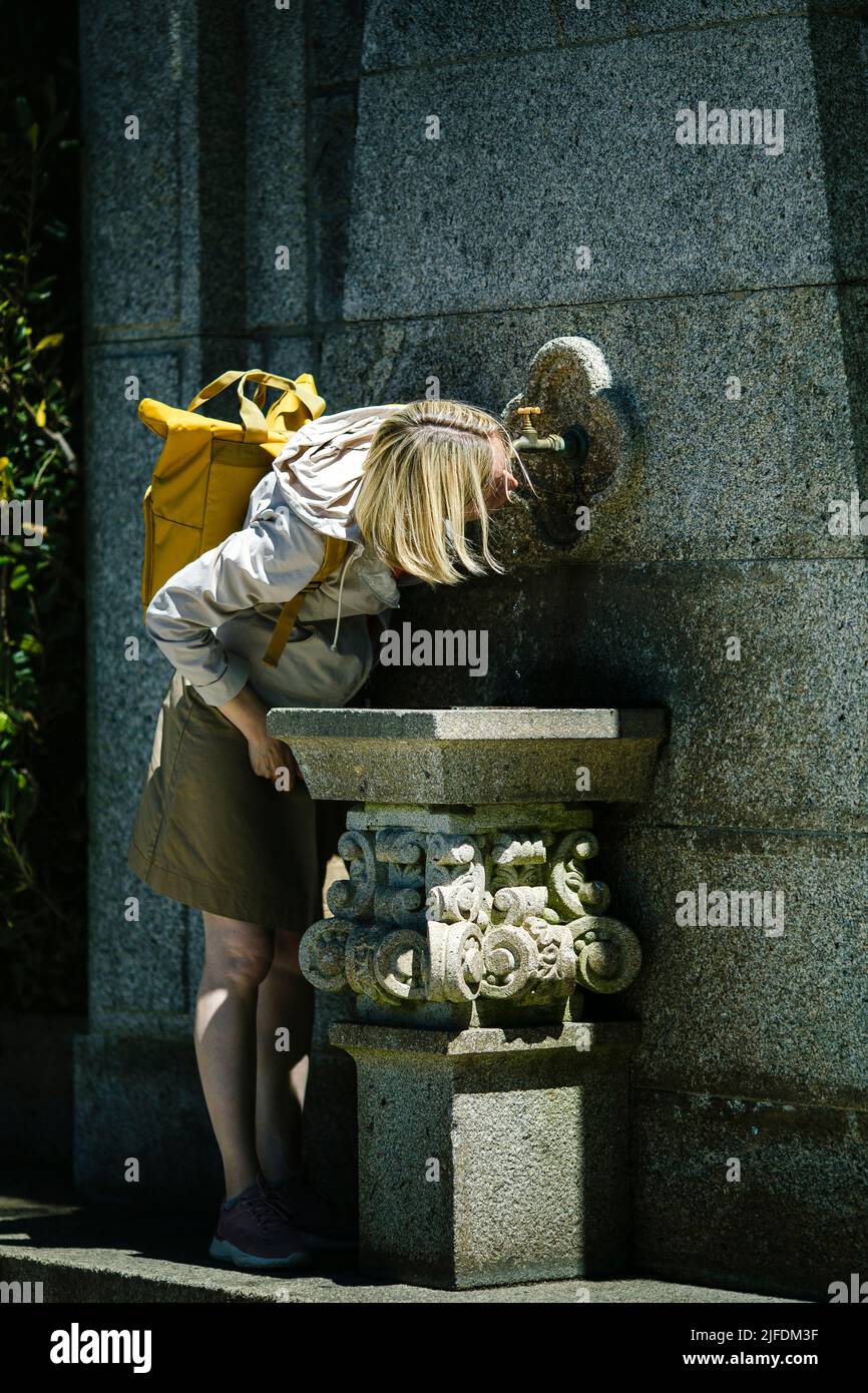 A female tourist drinking from a medieval drinking fountain Stock Photo ...