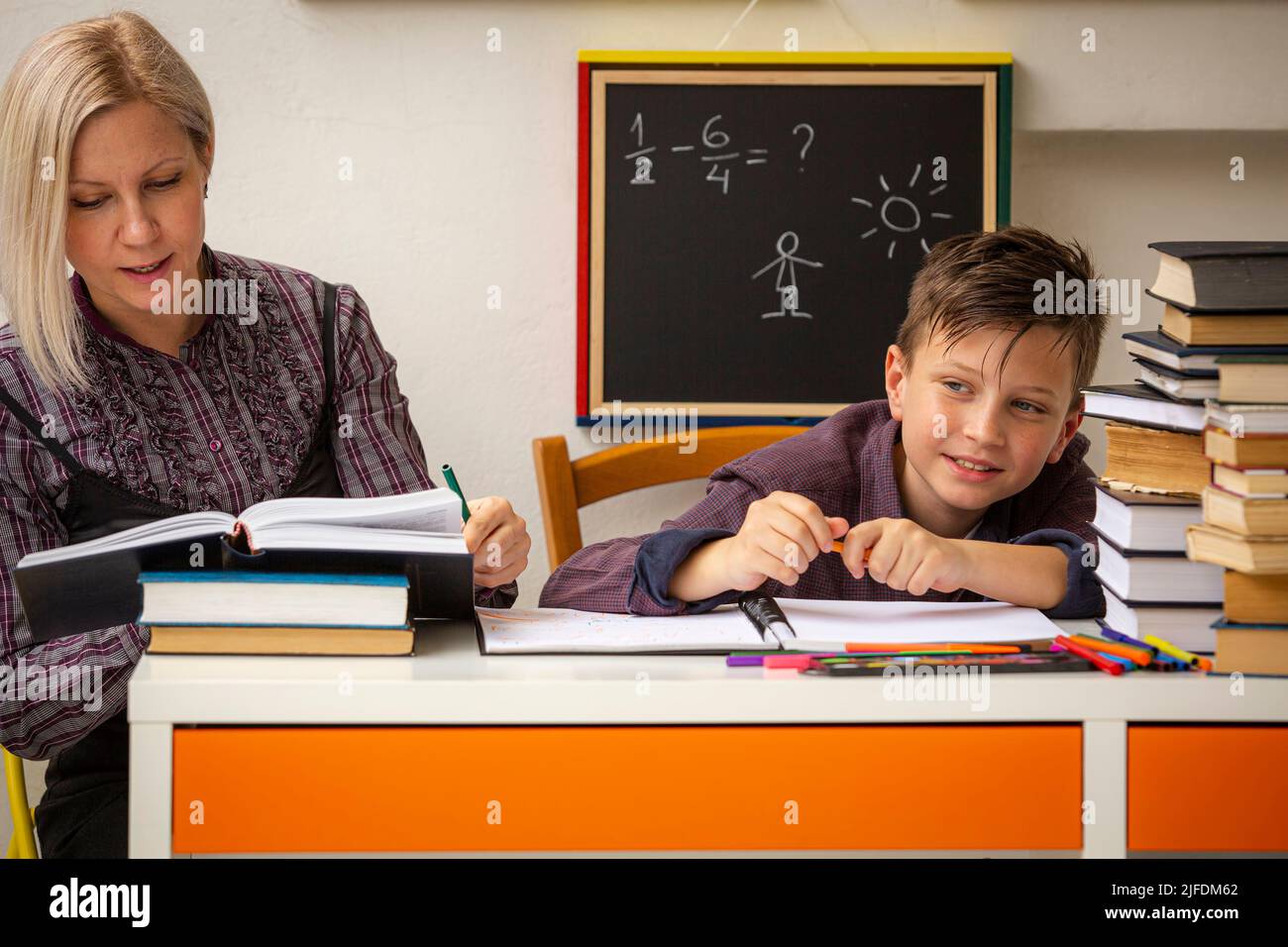 A junior high school student studies at home with a female tutor Stock ...