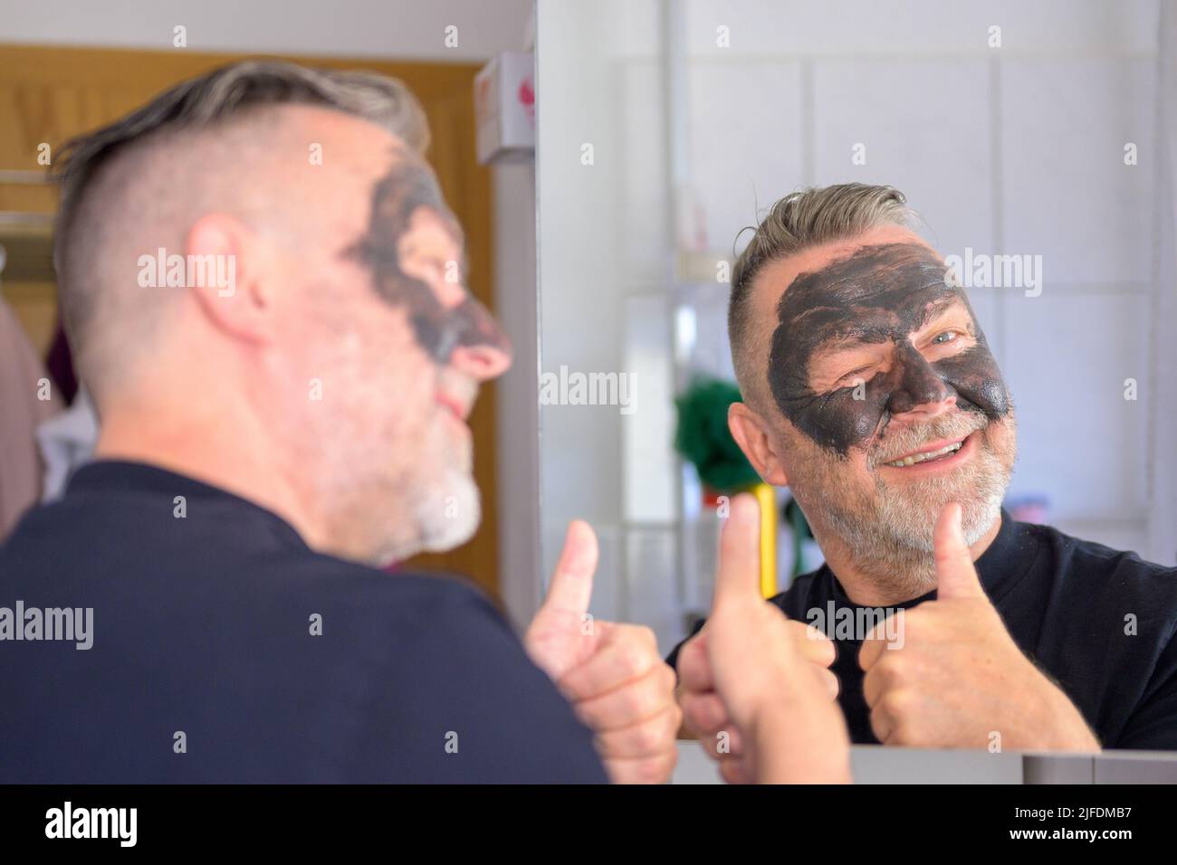 Man wearing a cosmetic face mask giving a thumbs up of approval with a ...