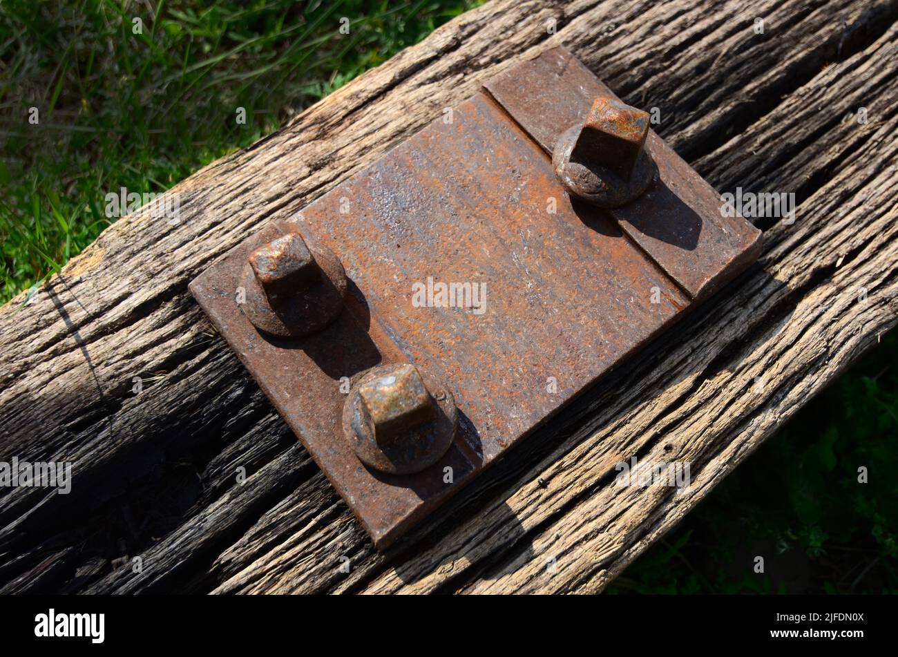 An abandoned old railway tie with a rusty bolt on an old cracked wooden ...