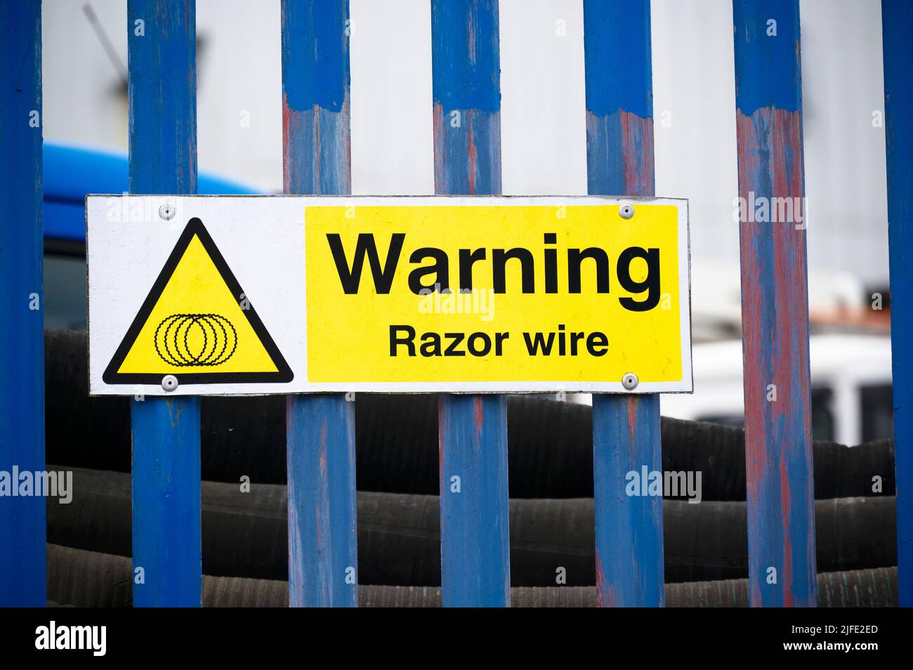 Razor wire warning sign on security fence at construction site Stock ...