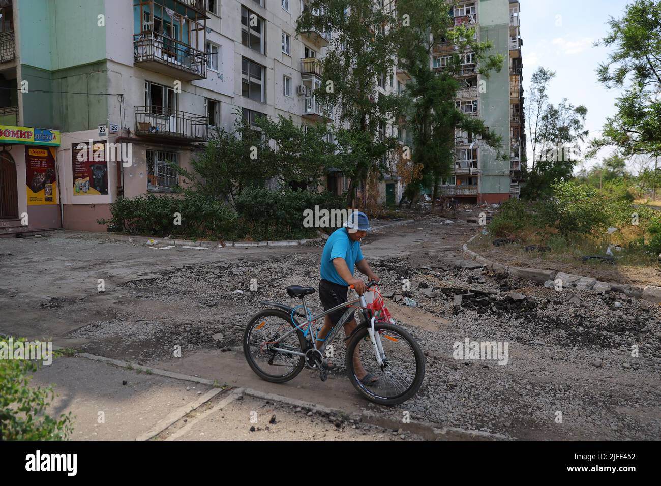 Severodonetsk. 1st July, 2022. A resident walks a bike past a building ...