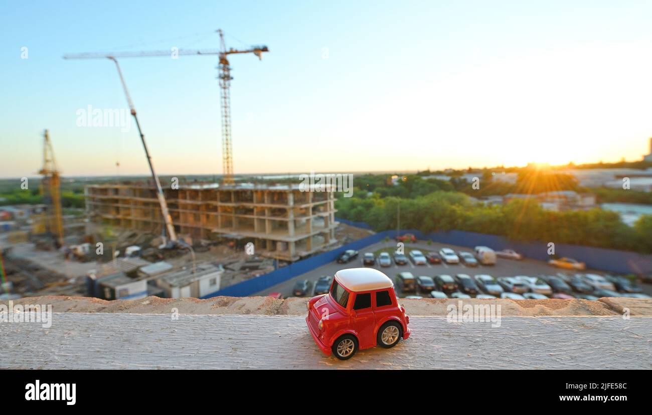 a small red toy car against the backdrop of a house under construction ...