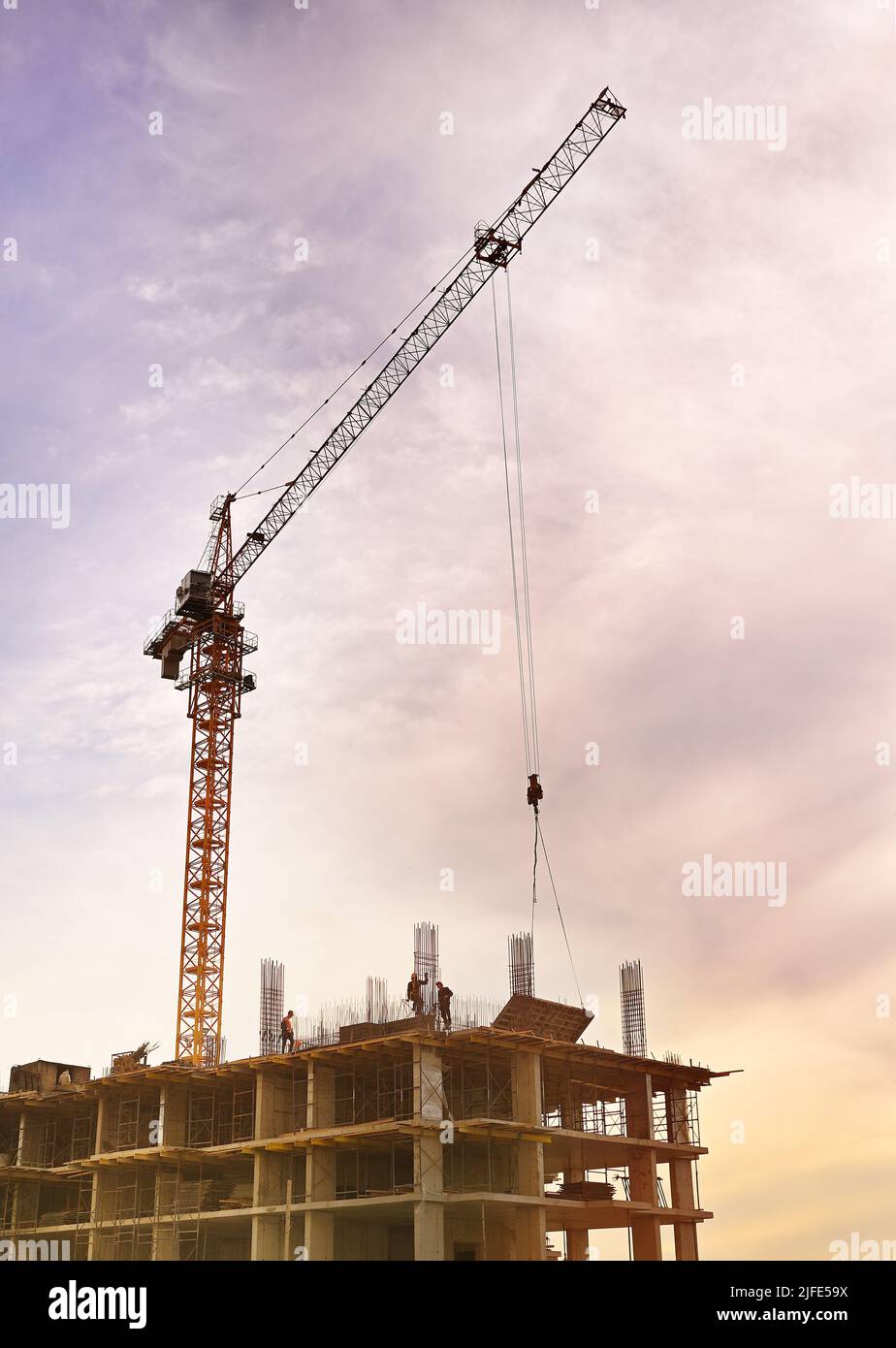 a construction crane lifts a concrete slab against the background of a ...