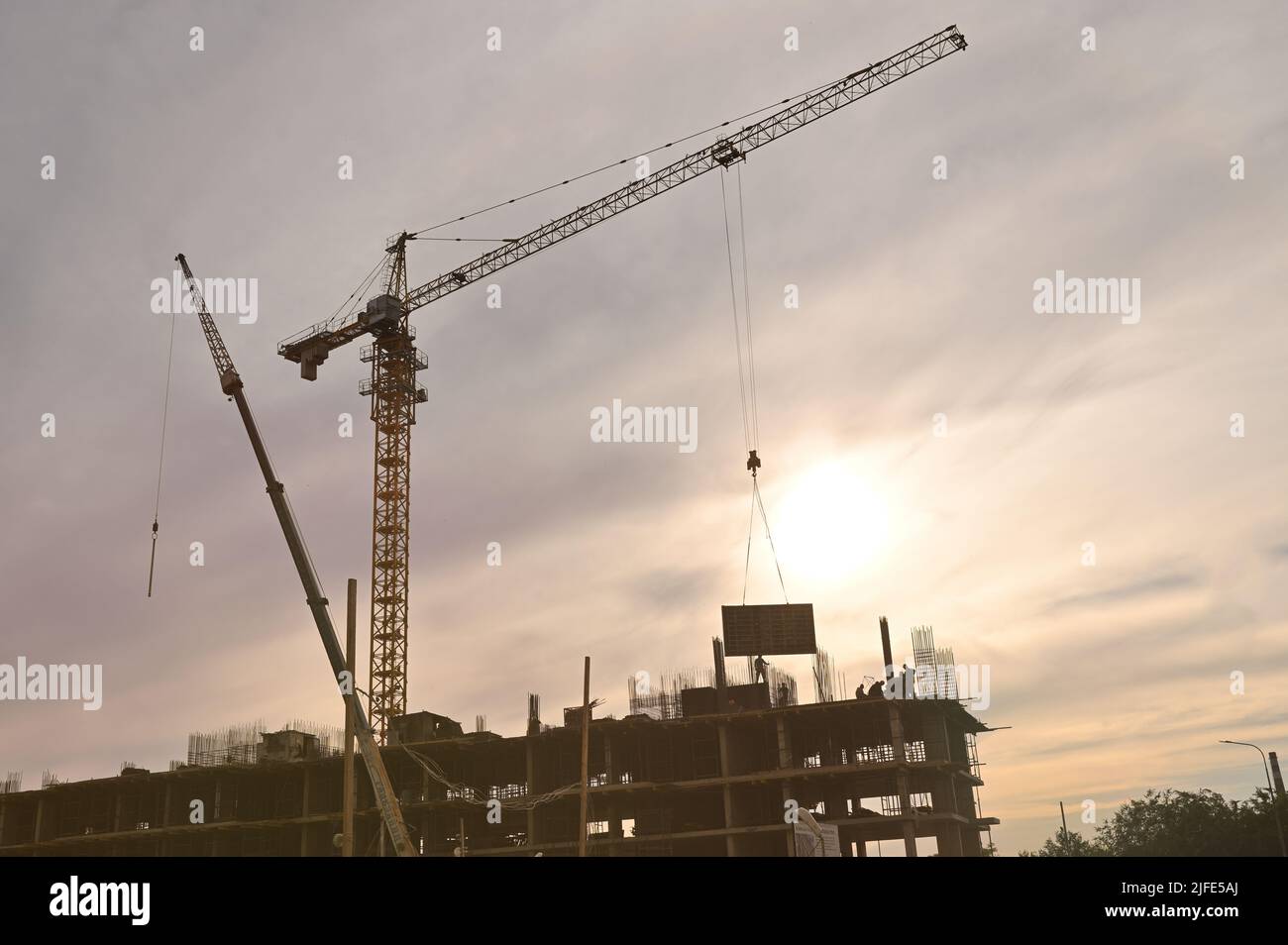 a construction crane lifts a concrete slab against the background of a ...