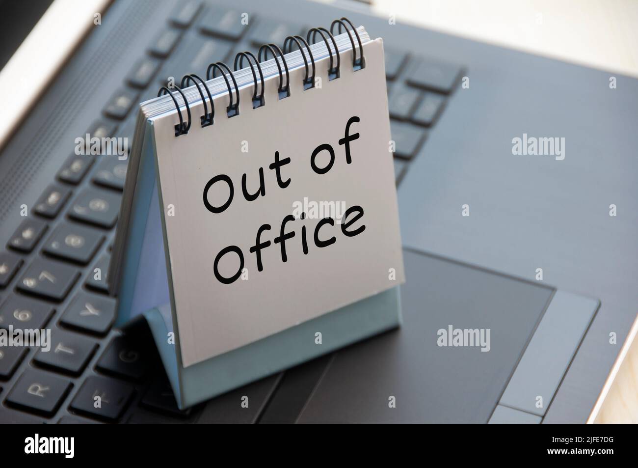 Out of office text on calendar desk on top of a laptop. Business ...
