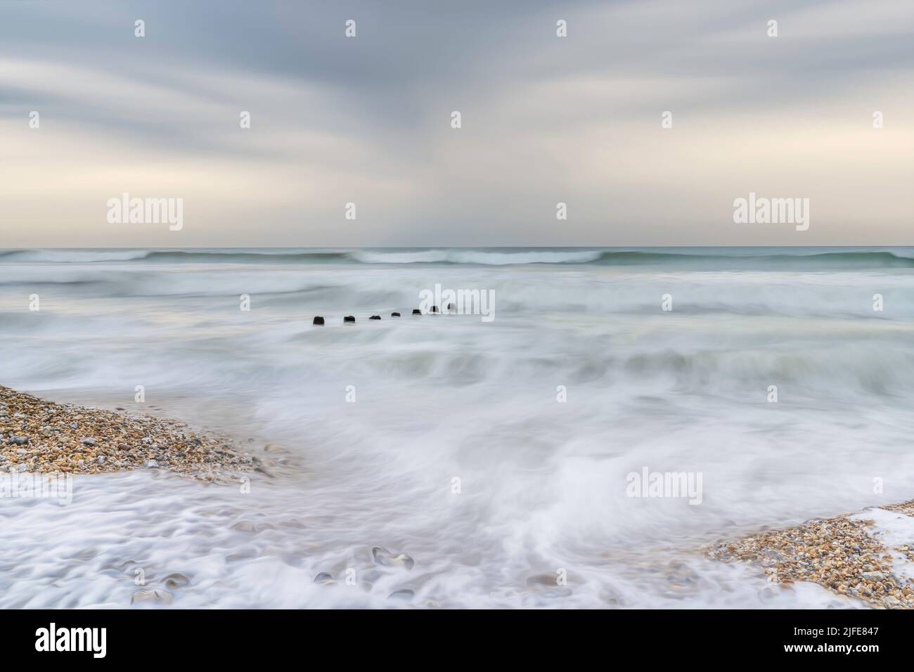 Milky, pastel shade seas, swirling around the beach and old groin at ...
