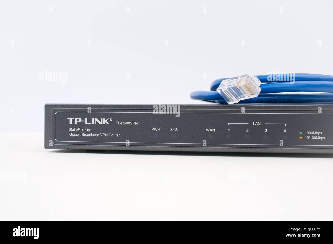 TP-LINK broadband network router with network cables on a white desk ...