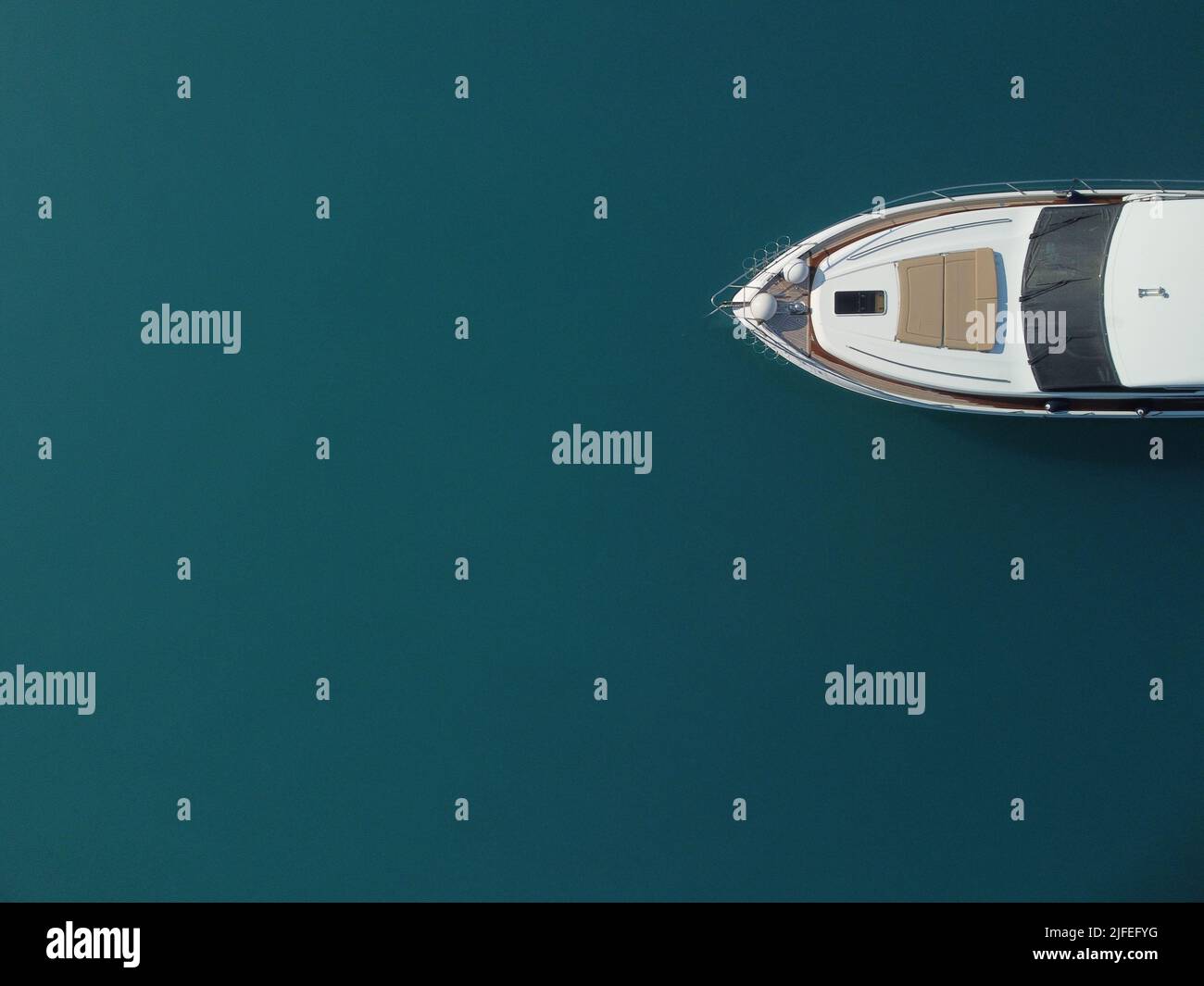 Aerial yacht on calm sea. Luxury cruise trip. View from above of white boat on deep blue water ...