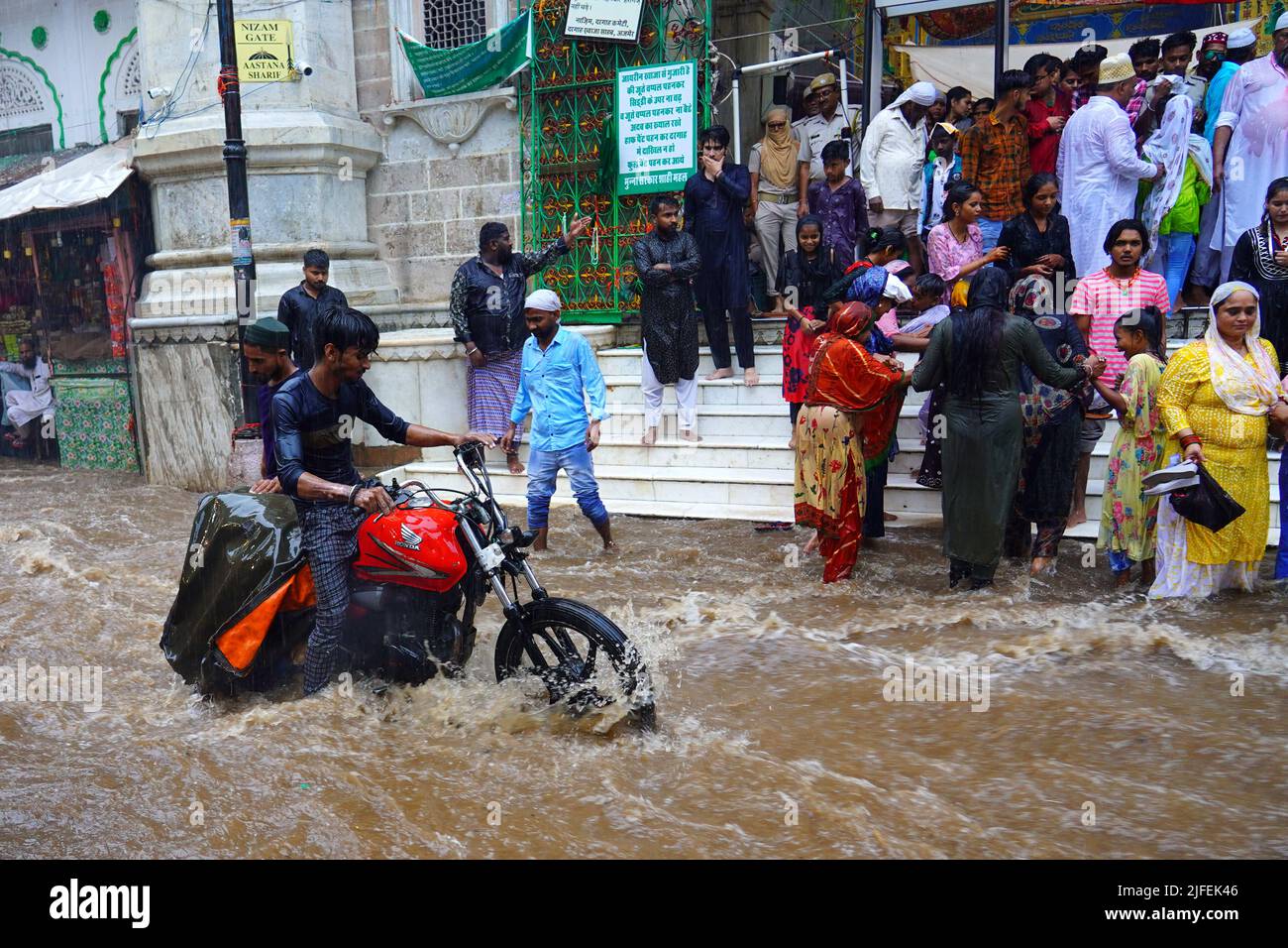 Indian People wade through a waterlogged street after a heavy monsoon ...