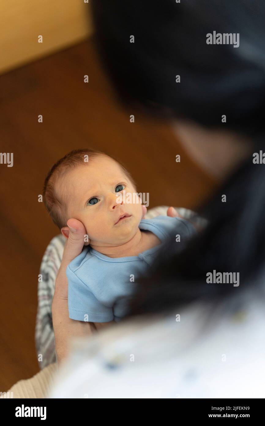 Small newborn baby looking attentively at mother Stock Photo - Alamy