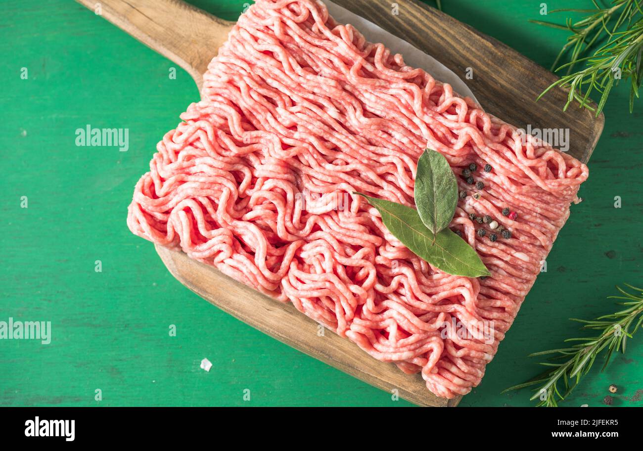 Raw Mince, minced Ground beef meat on a cutting board. Green background ...