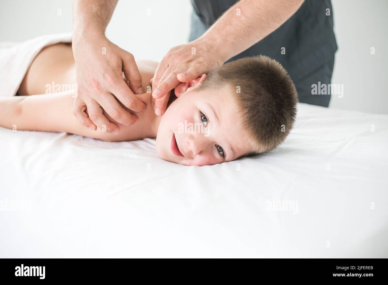 Boy toddler relaxes from a therapeutic massage. Physiotherapist working ...