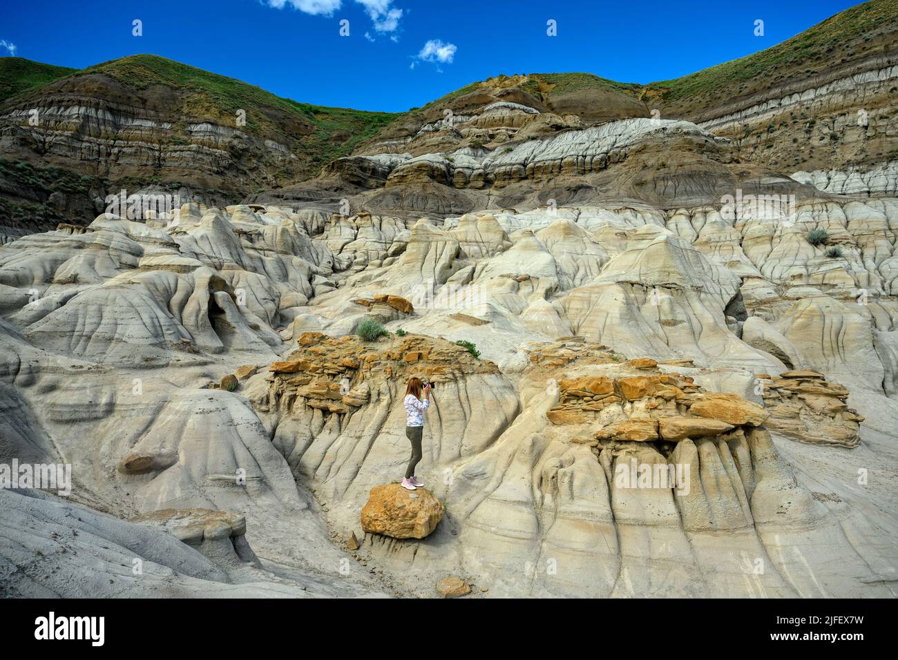 Tourist woman standing on a sandstone and photographing the Hoodoos and ...
