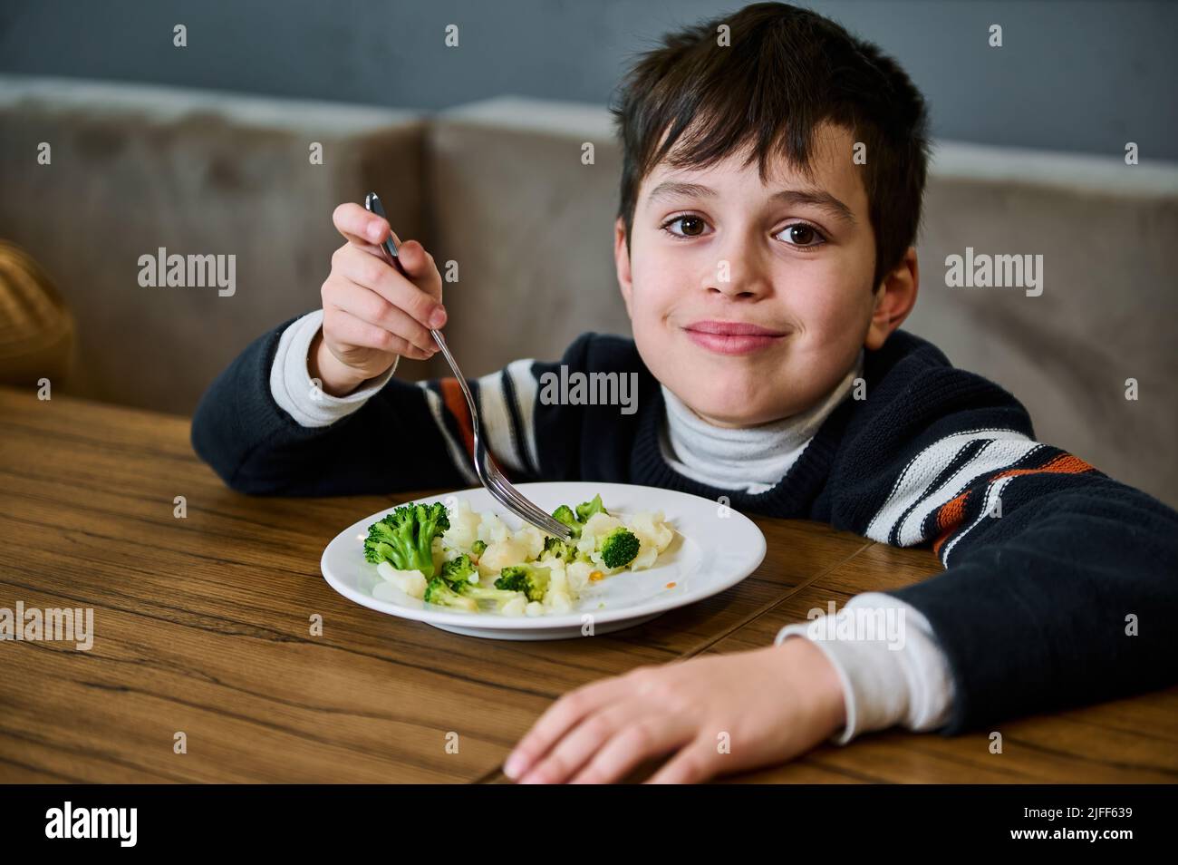 Handsome dark-haired Caucasian school age boy eating healthy vegan meal ...