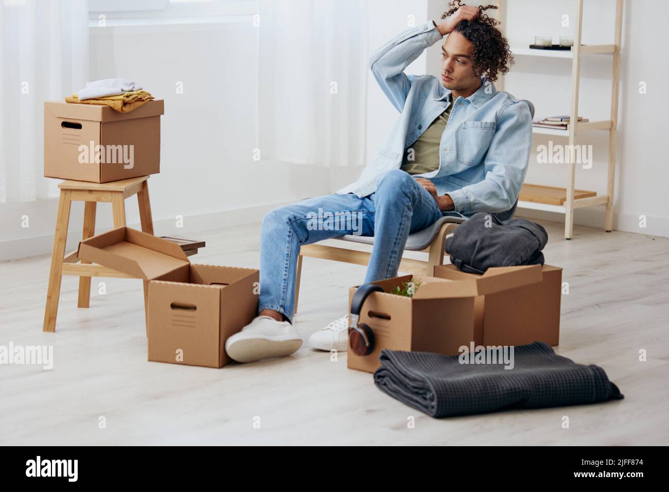 handsome guy sitting on a chair unpacking with box in hand moving ...
