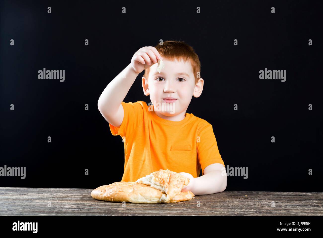 beautiful red haired boy with a delicious loaf of bread ,boy eats bread ...