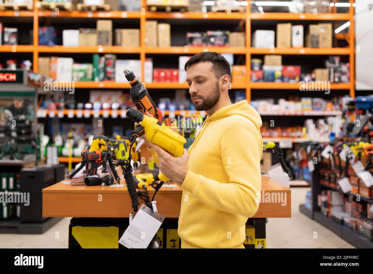 a young man compares two drills in a power tool store Stock Photo - Alamy