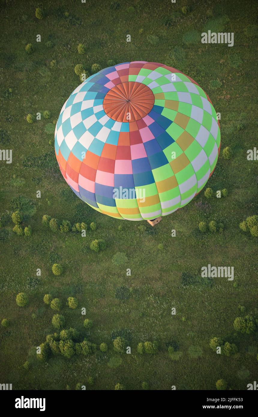 A colorful traveling air balloon flying over the field using heat ...