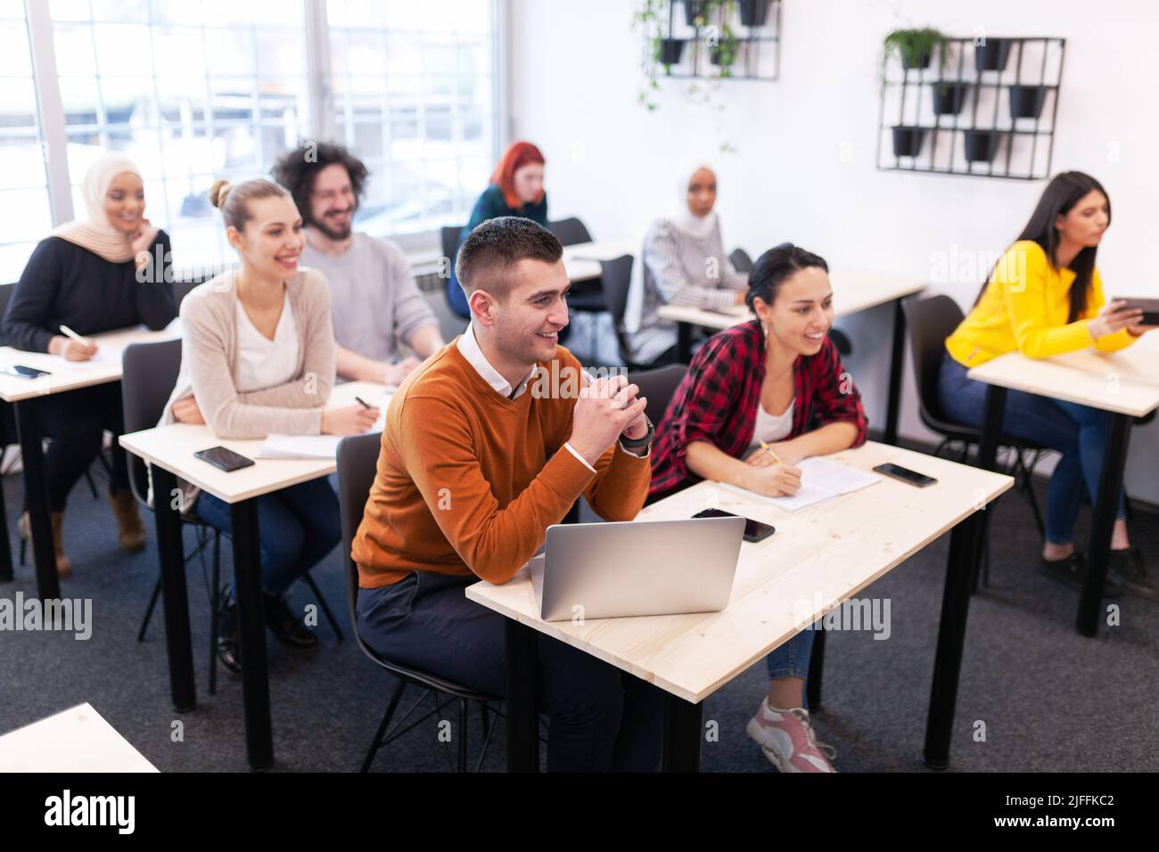 Multi ethnic students listening to a lecturer in a classroom. Smart ...