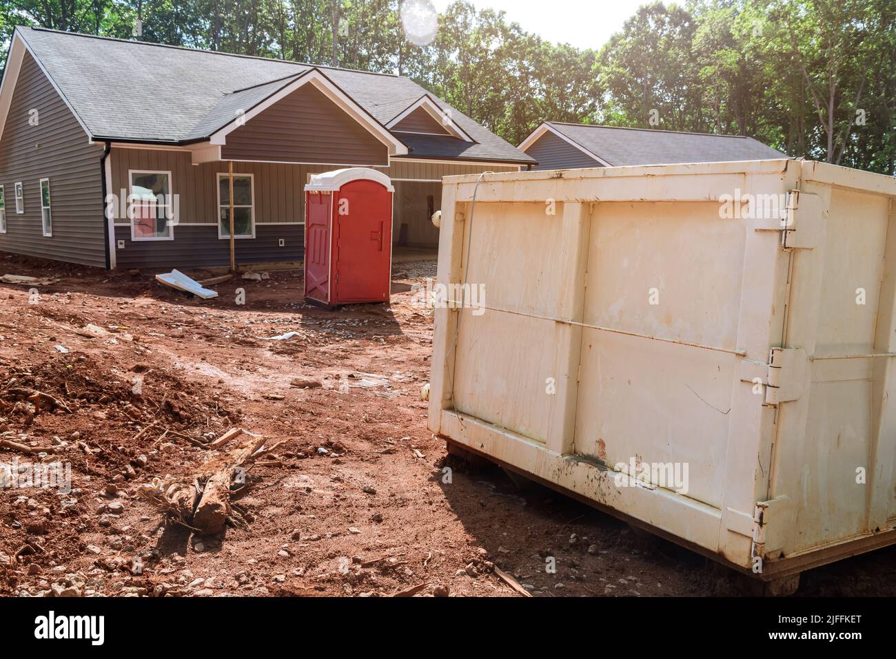 Construction garbage dumpster and portable restroom on new house under ...