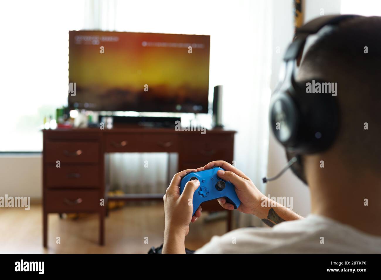 Person playing video game with remote control, wireless headphones and ...