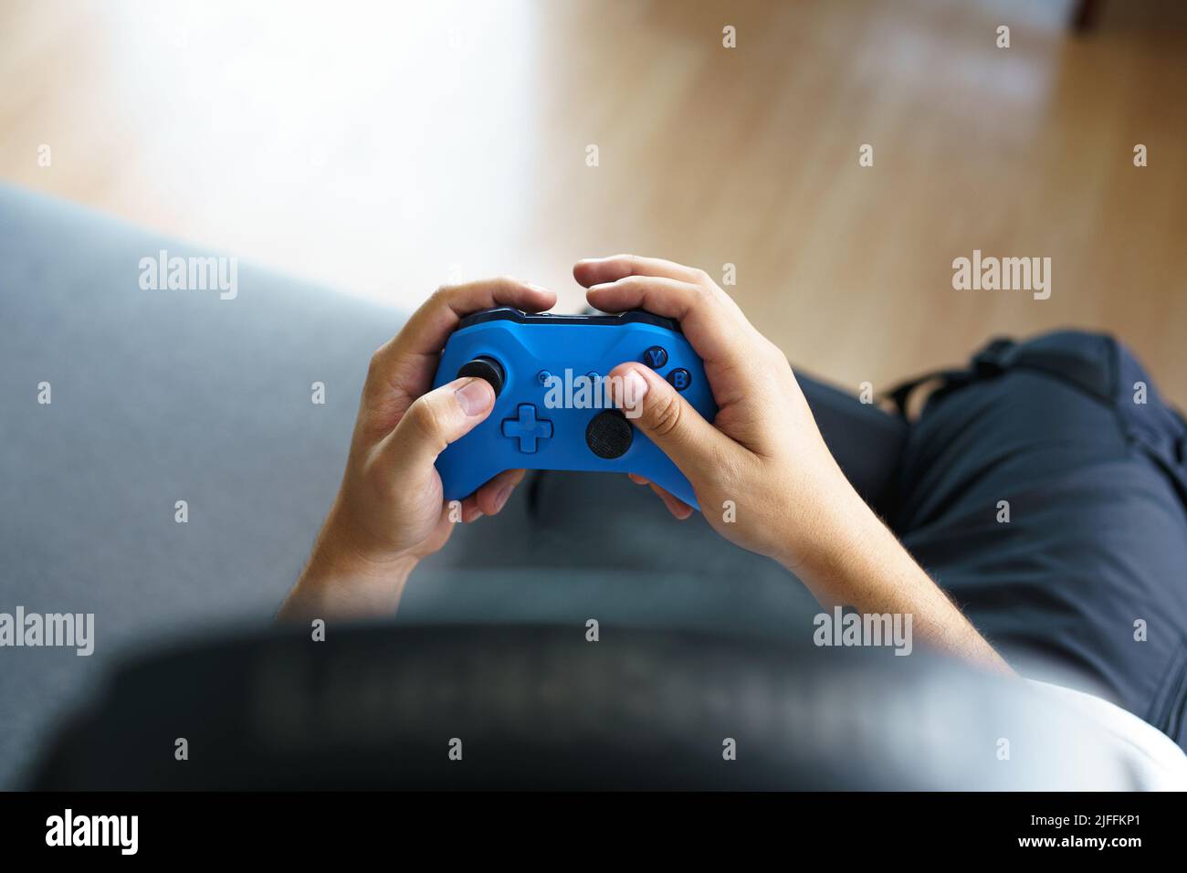 hands holding and playing with a blue video game controller, details of ...