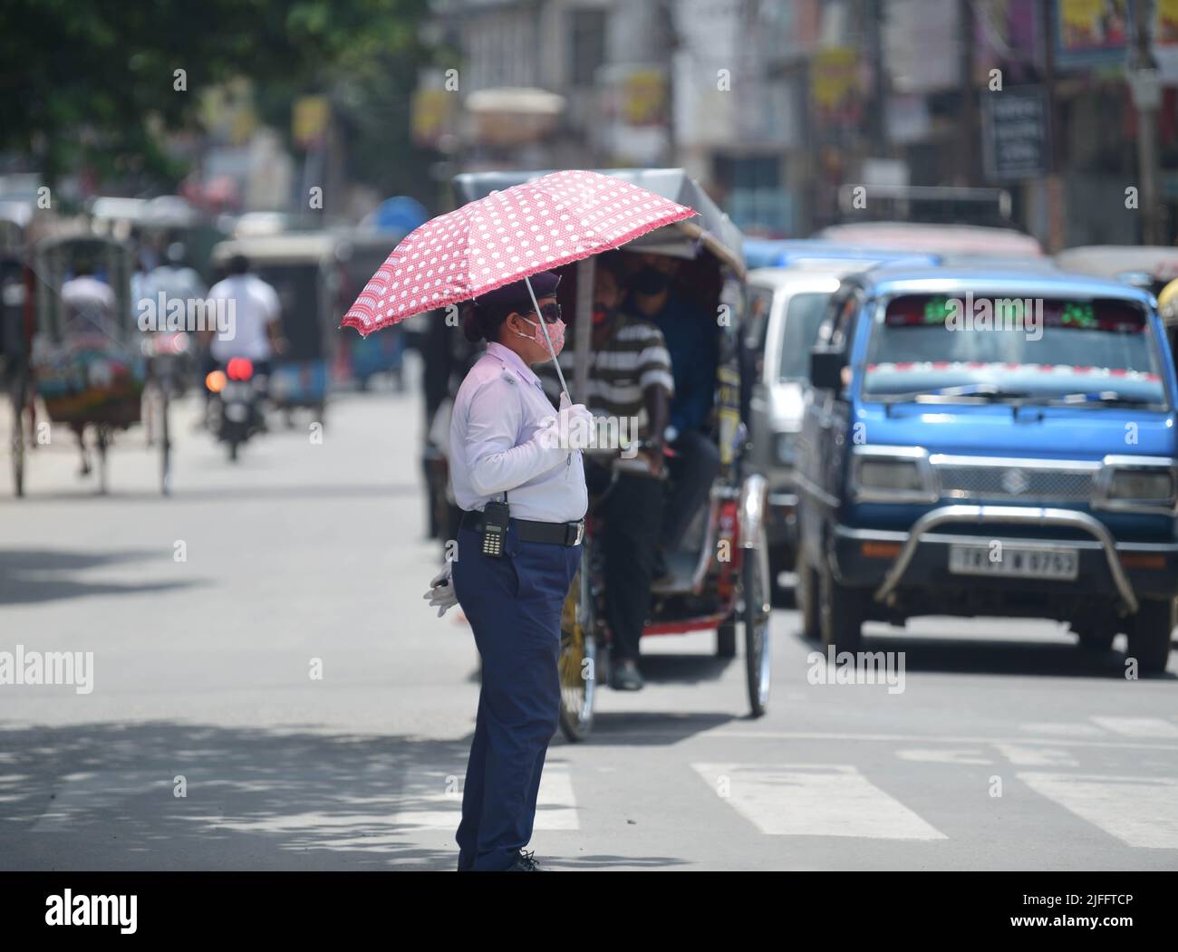 A female traffic police officer maintaining traffic with an umbrella on ...