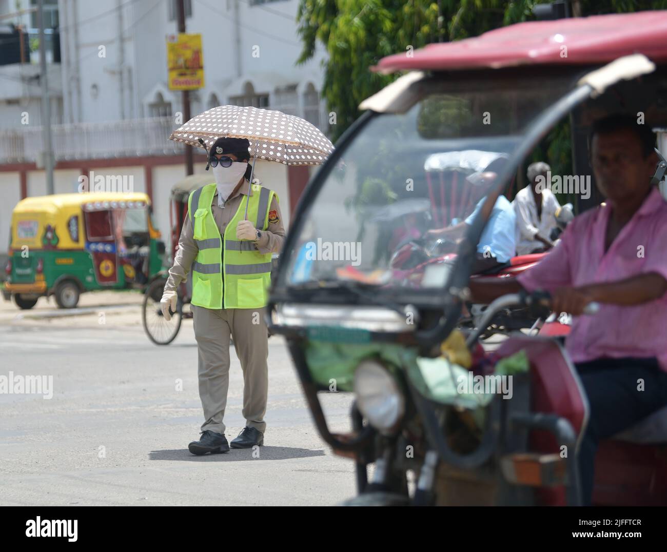 A female traffic police officer maintaining traffic with an umbrella on ...