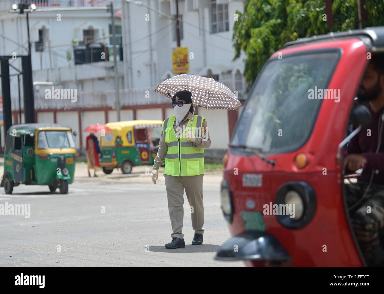 A female traffic police officer maintaining traffic with an umbrella on ...