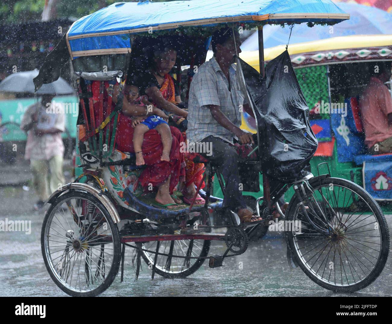 Commuters taking a rickshaw ride which is covered in polythene during ...