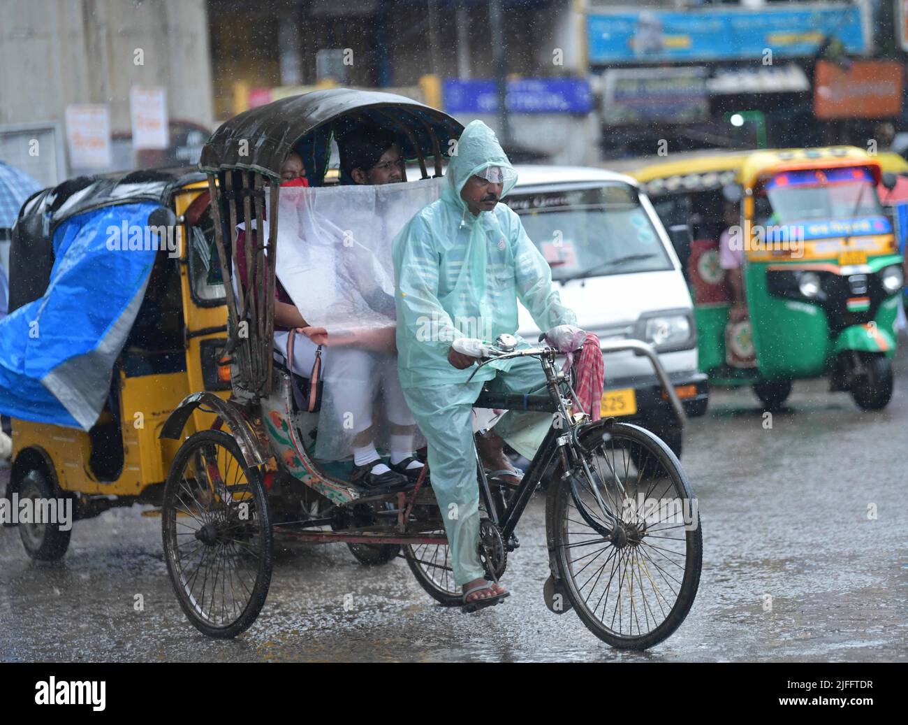 Commuters taking a rickshaw ride which is covered in polythene during ...