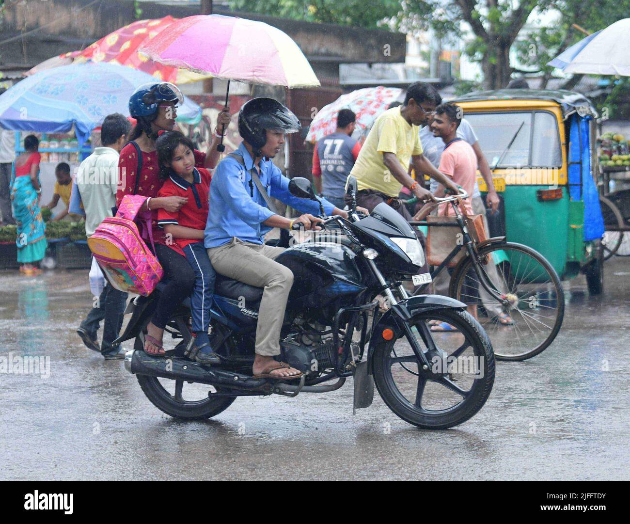 Commuters traveling by bike during heavy rain in Agartala. Tripura ...