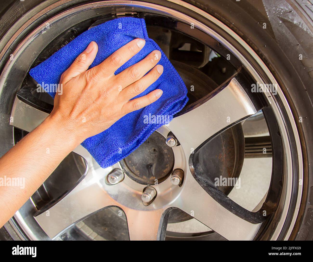 Hand with microfiber cloth cleaning wheel car Stock Photo - Alamy