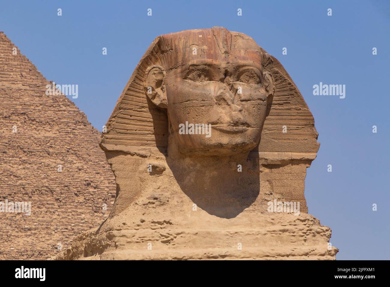 the Great Sphinx in front of pyramid of Khafre in Giza against blue sky ...